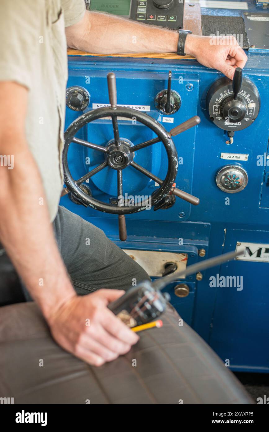 This image captures a ship captain at the helm of a maritime vessel ...