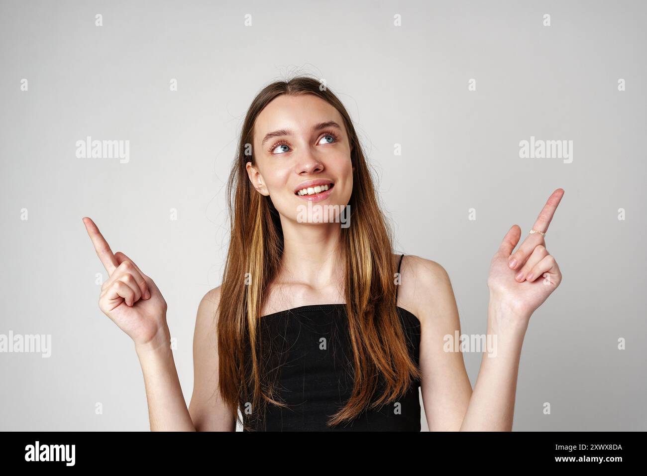 Young Woman Pointing Upwards With a Smile Stock Photo - Alamy