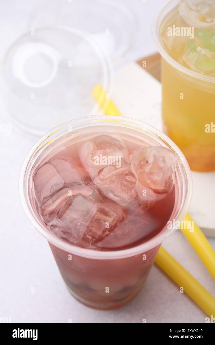 Tasty bubble tea in plastic cups and straws on light table, closeup ...