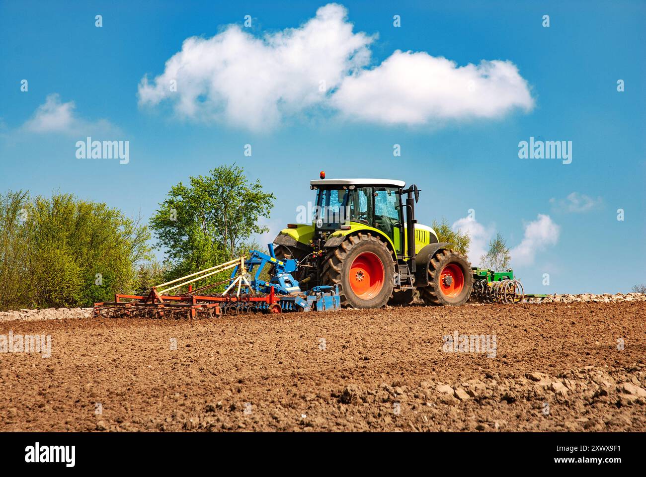 Tractor with harrow and cultivator in the field during tillage Stock ...