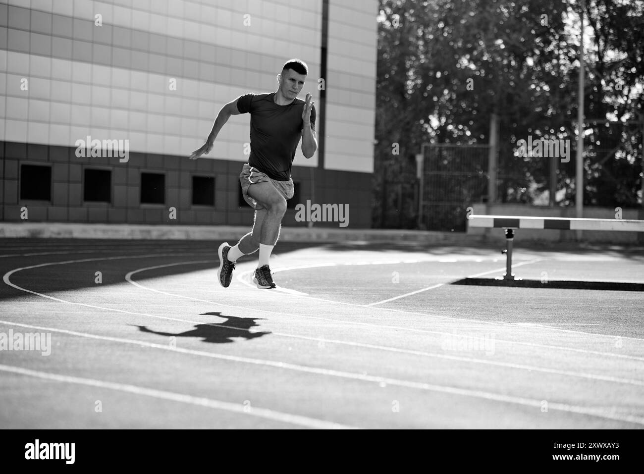 Black and white photo. Focused runner sprints around track, his ...