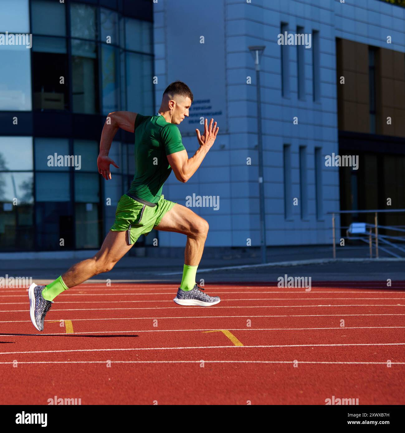 Focused man, athlete, runner sprints around track, his determined ...