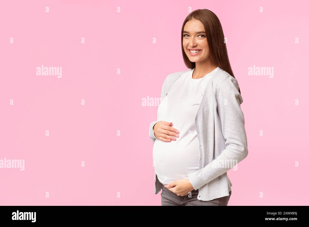 Joyful Expectant Woman Touching Belly Posing Over White Studio ...