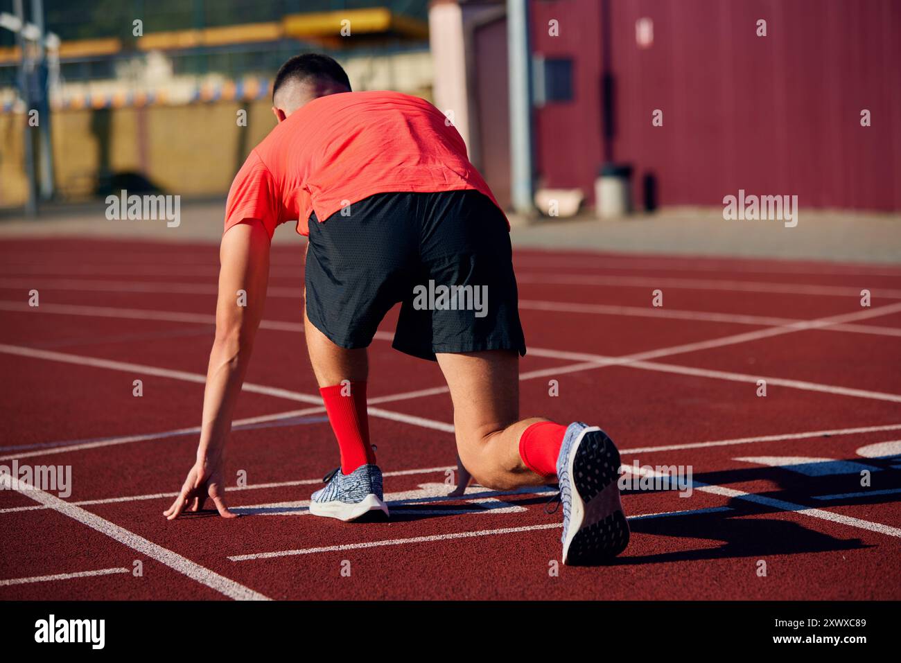 Back view photo of young man, ready to run standing on start line in ...