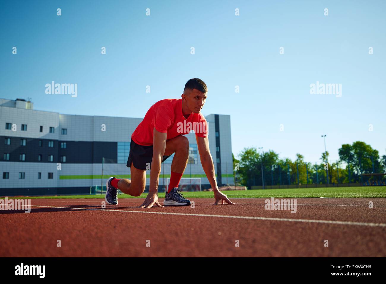 Low angle photo of young man, ready to run standing on start line in ...