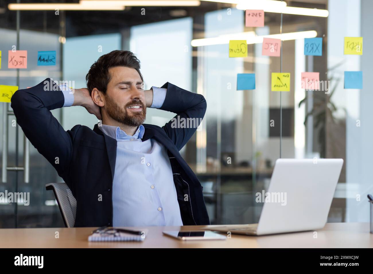 Confident businessman takes break at desk, leaning back with relaxed ...
