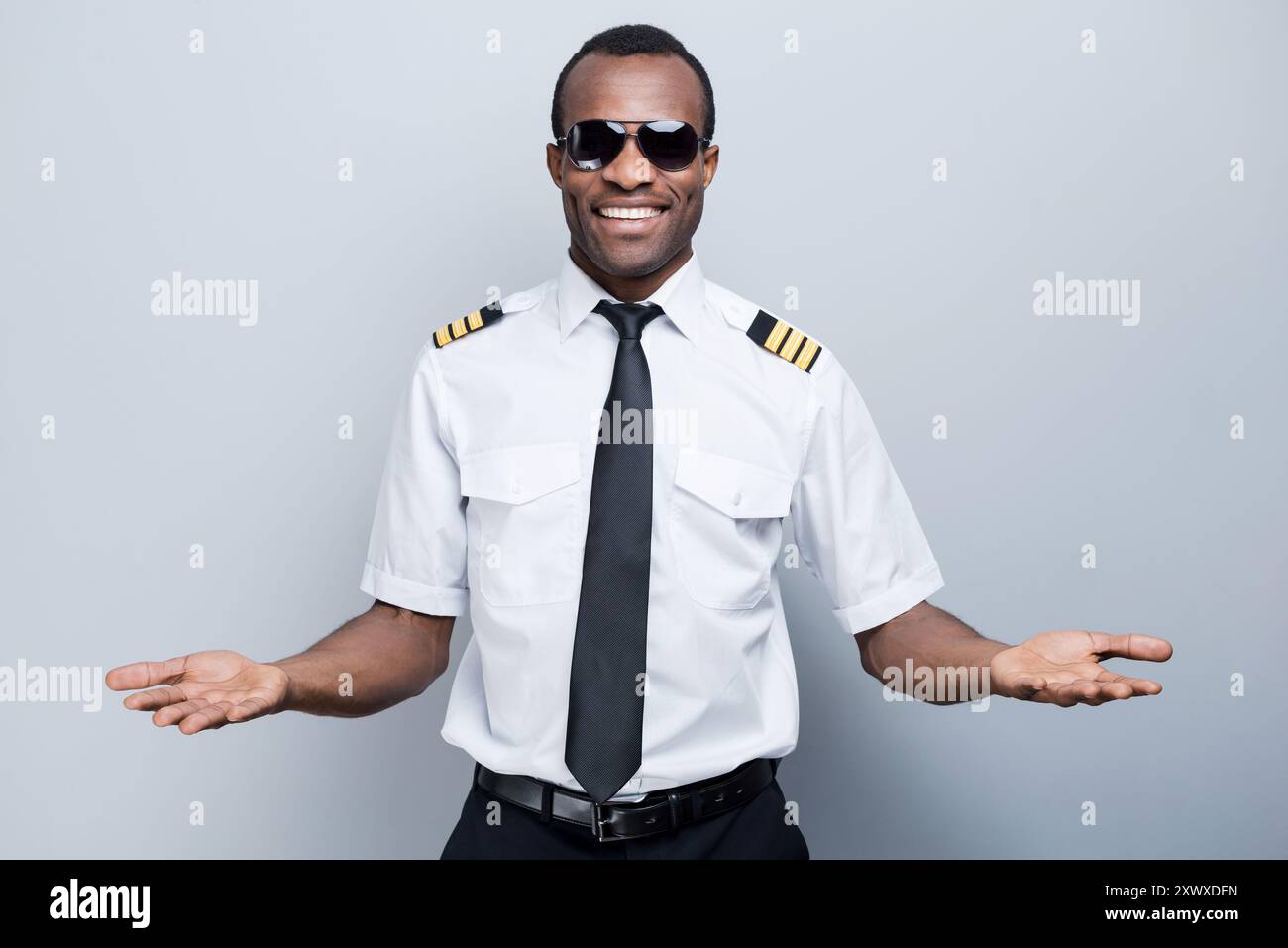 Welcome on board! Happy African pilot in uniform gesturing welcome sign ...