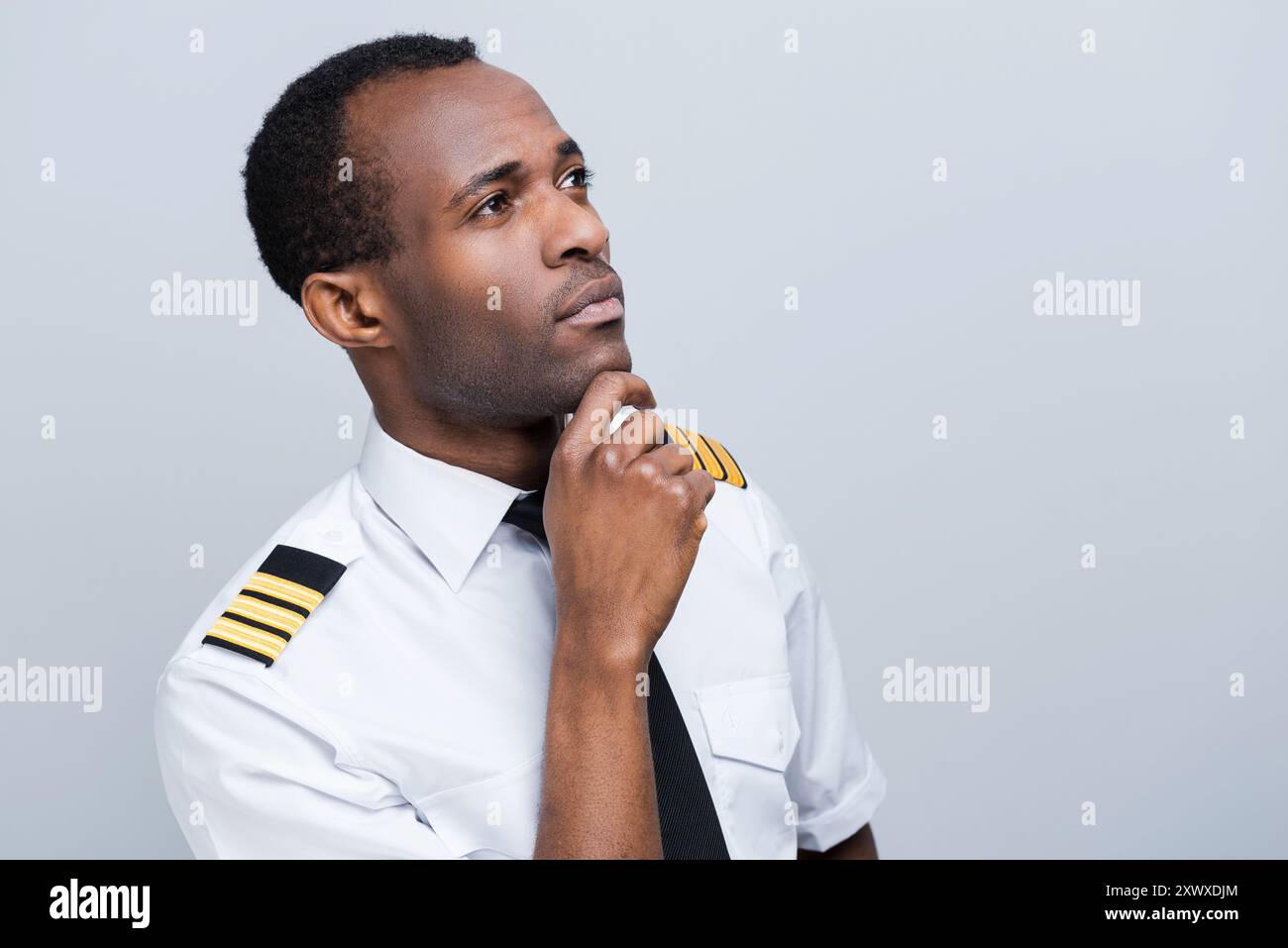 Thoughtful pilot. Side view of thoughtful African pilot in uniform ...