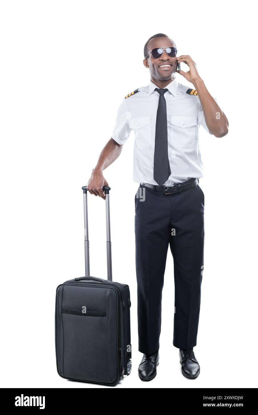 Always on the go. Confident African pilot in uniform leaning hand on ...