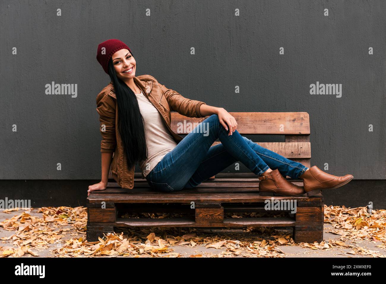 Trendy beauty. Beautiful young woman sitting on the wooden pallet and ...