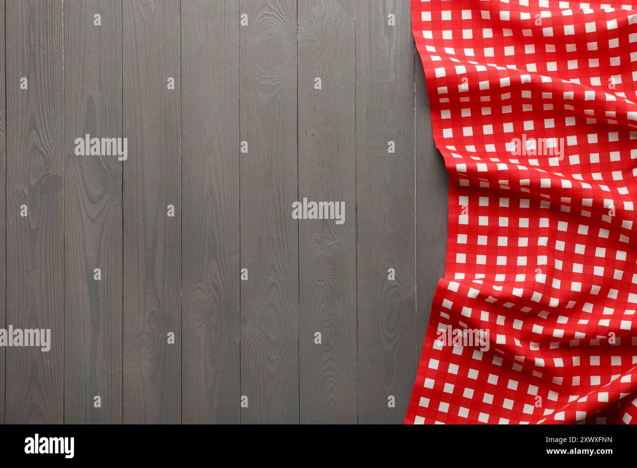 Red checkered picnic tablecloth on grey wooden table, top view. Space ...