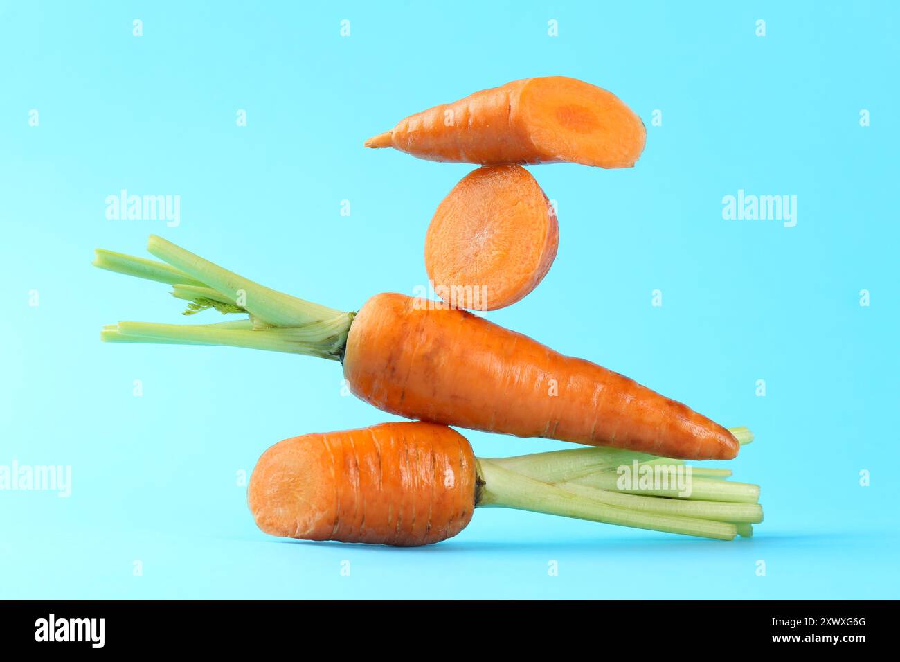 Whole and cut fresh carrots on light blue background Stock Photo - Alamy