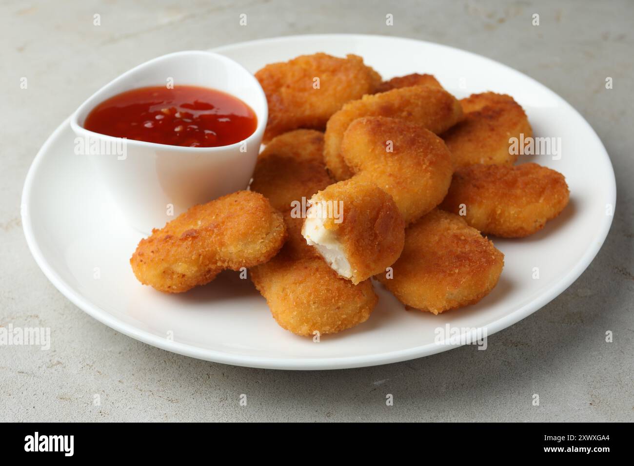 Tasty chicken nuggets with chili sauce on grey textured table Stock ...
