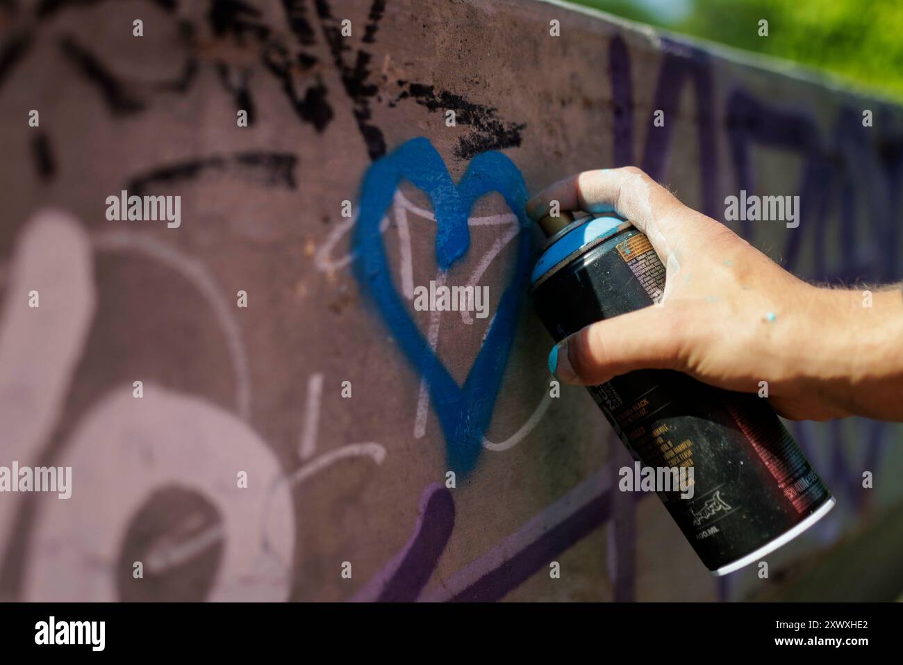 A man sprays graffiti on a wall with a spray can. Berlin, August 14 ...