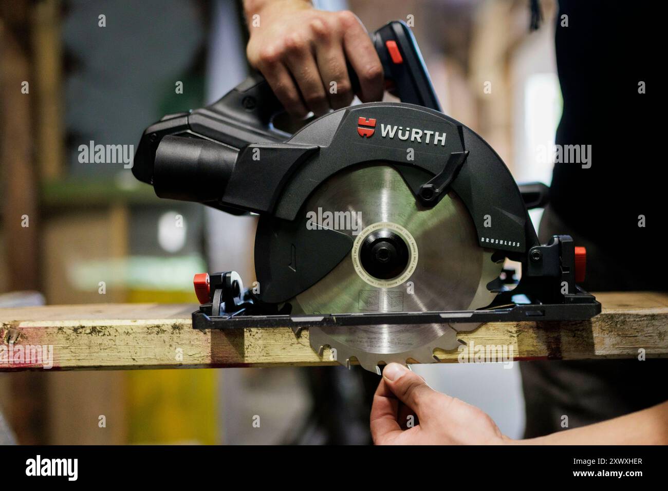 A man adjusts the cutting depth of a hand-held circular saw. Berlin ...