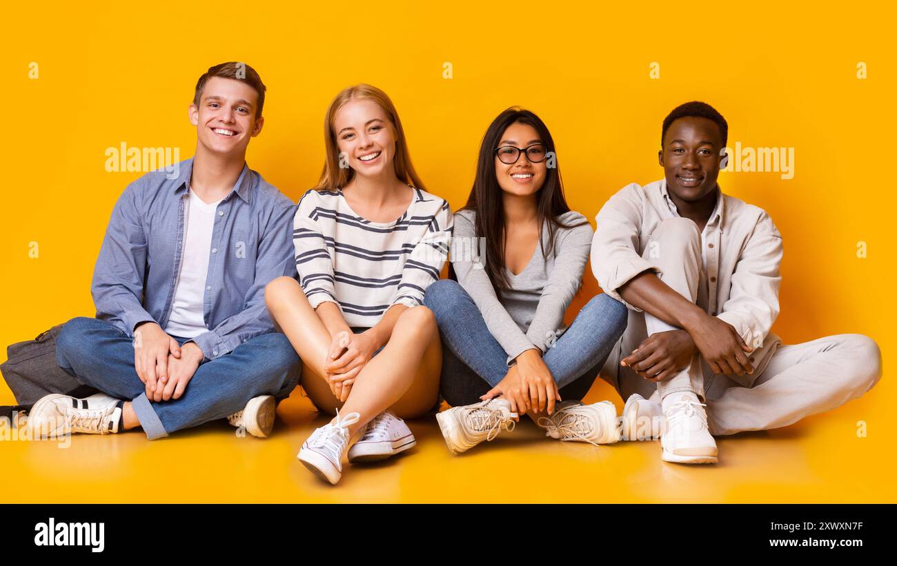 Happy students posing over yellow studio background Stock Photo - Alamy
