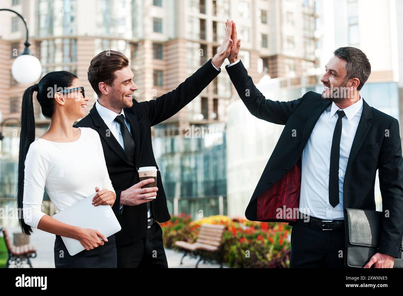 Celebrating success. Two happy young businessmen giving high five while ...