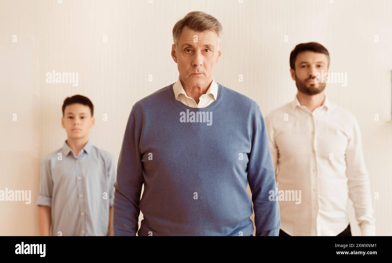 Serious Grandfather With Son And Grandson Standing Against Wall Indoor ...