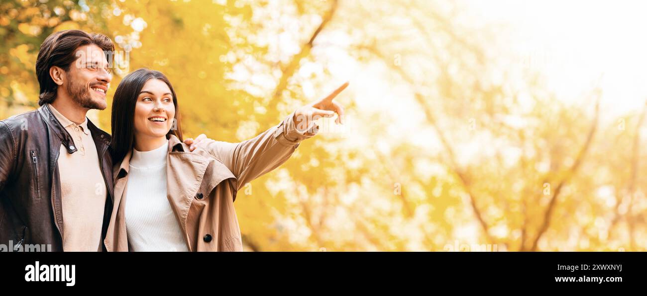 Excited woman showing something her boyfriend, pointing at copy space ...