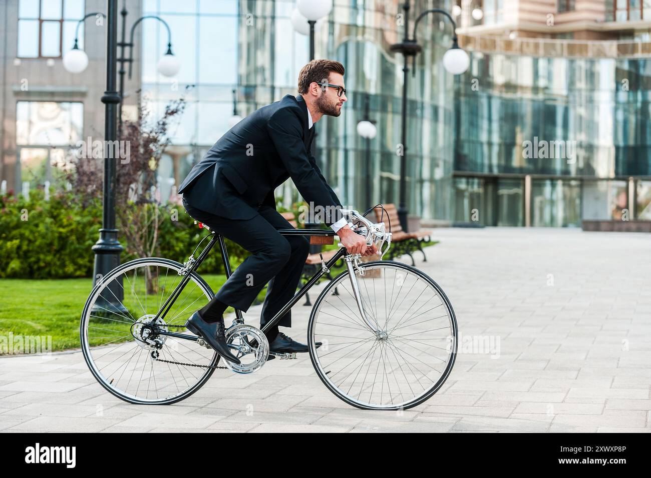 Going everywhere by his bike. Side view of young businessman looking ...