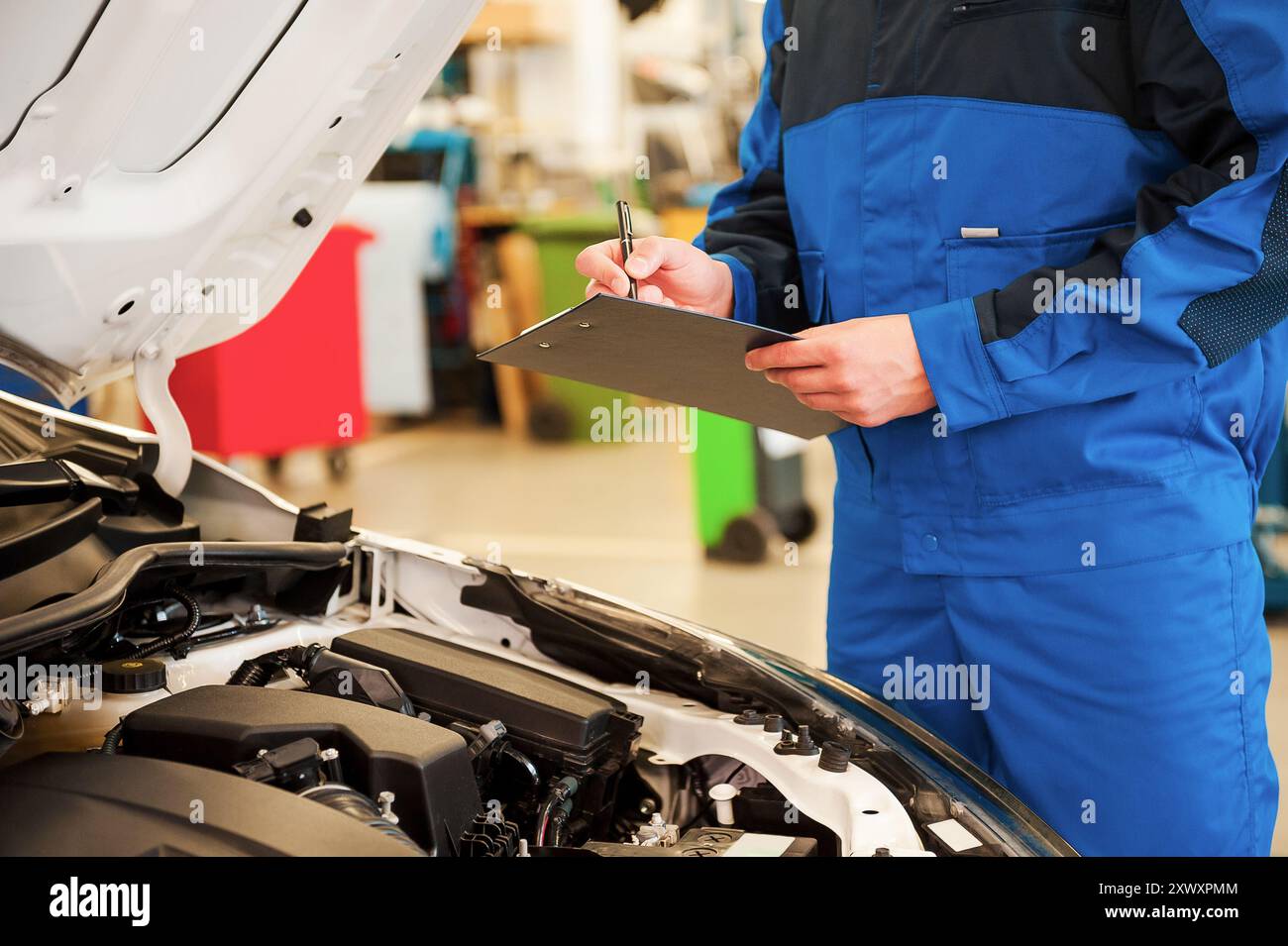 Taking a look under a hood. Close-up of man in uniform examining car ... Taking a look under a hood. Close-up of man in uniform examining car ...