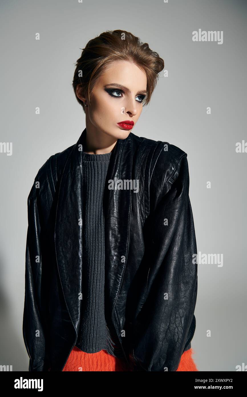 A woman with dark makeup and a leather jacket poses in a studio Stock ...