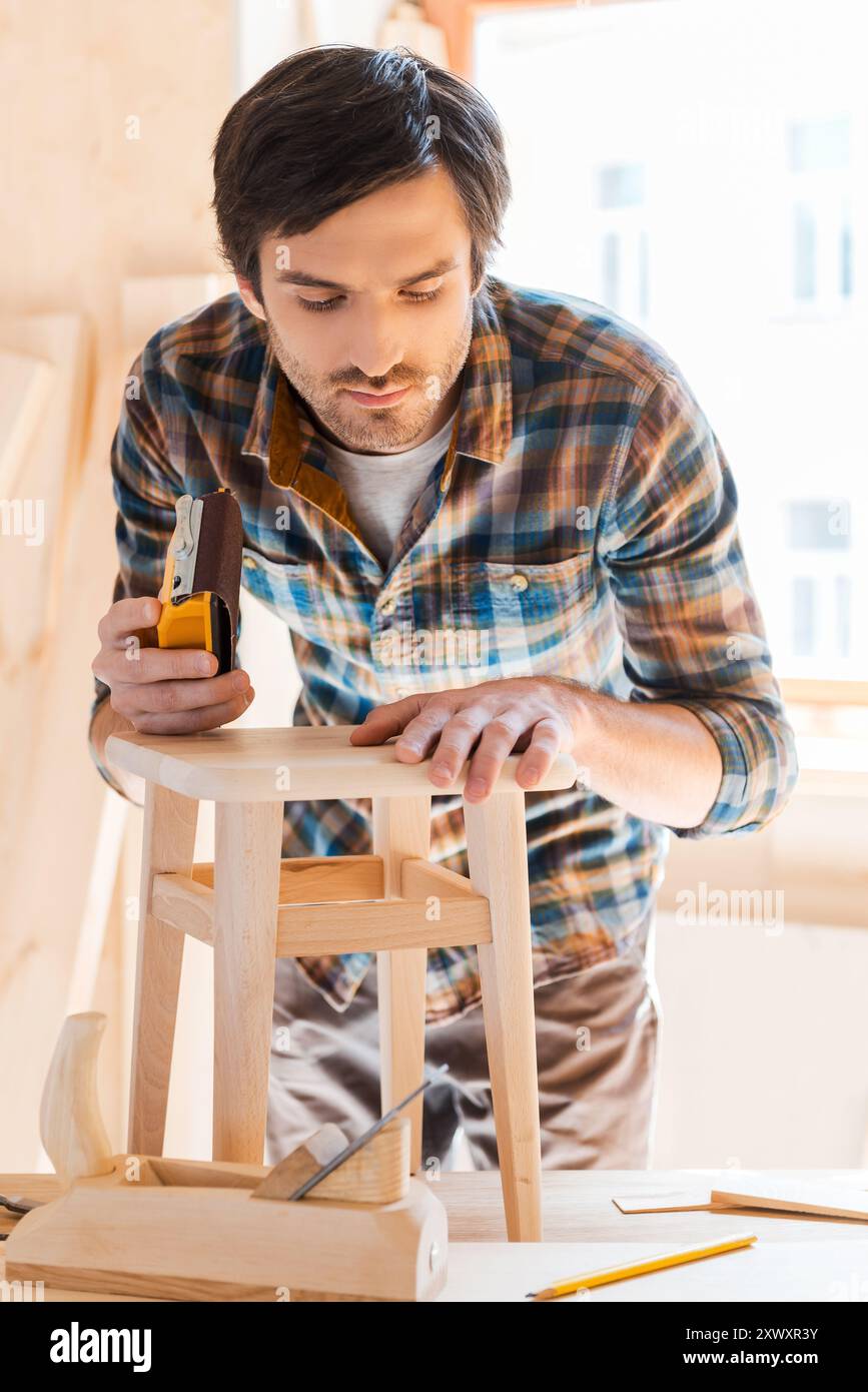 Working with wood is his passion. Concentrated young male carpenter ...