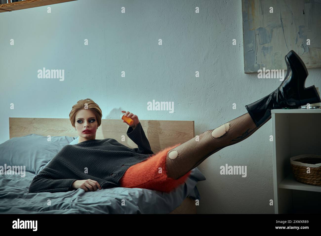 A woman in a stylish grunge outfit poses on a bed with legs extended ...