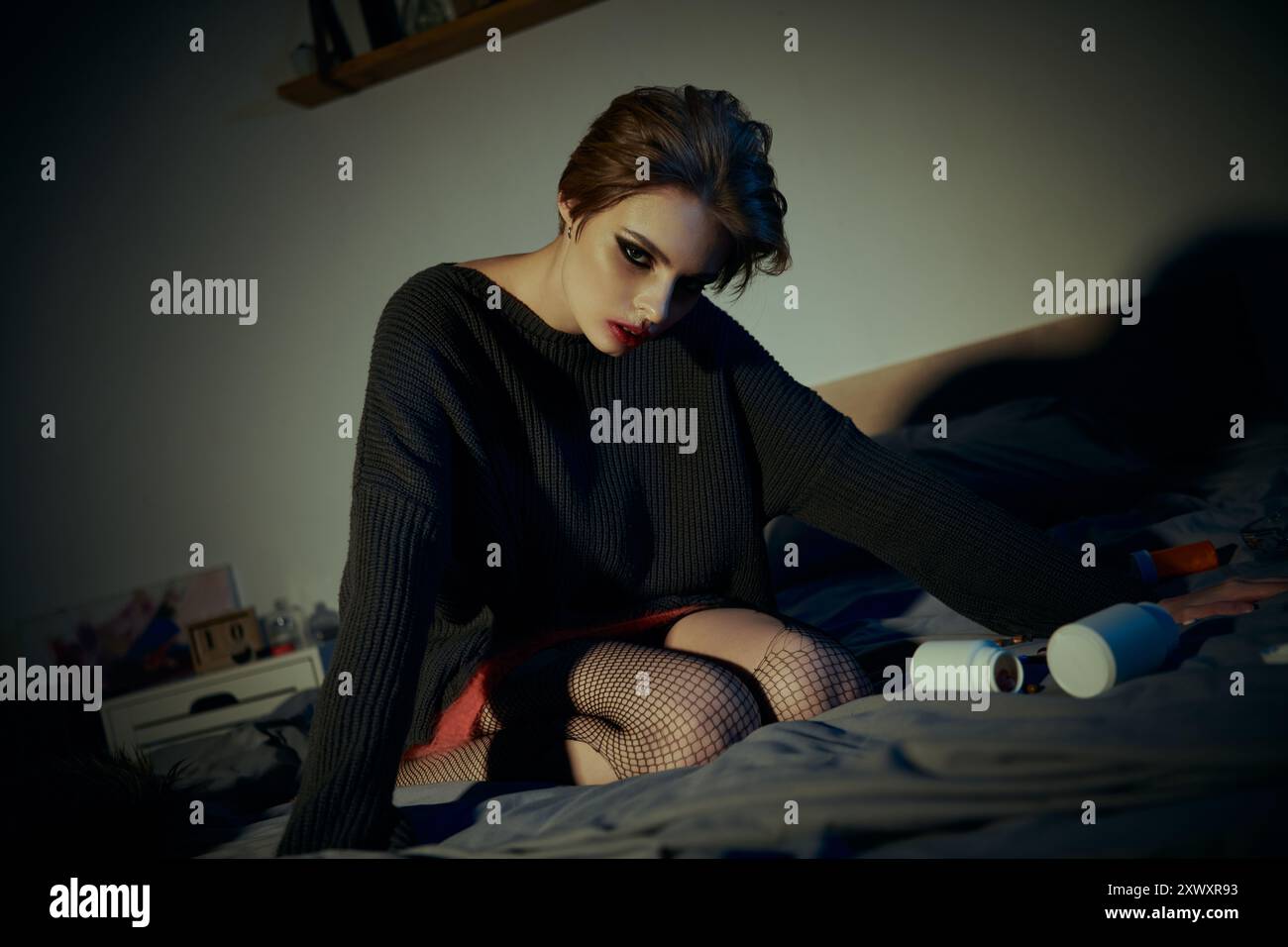 A woman dressed in grunge-inspired fashion poses on a bed in a dimly ...