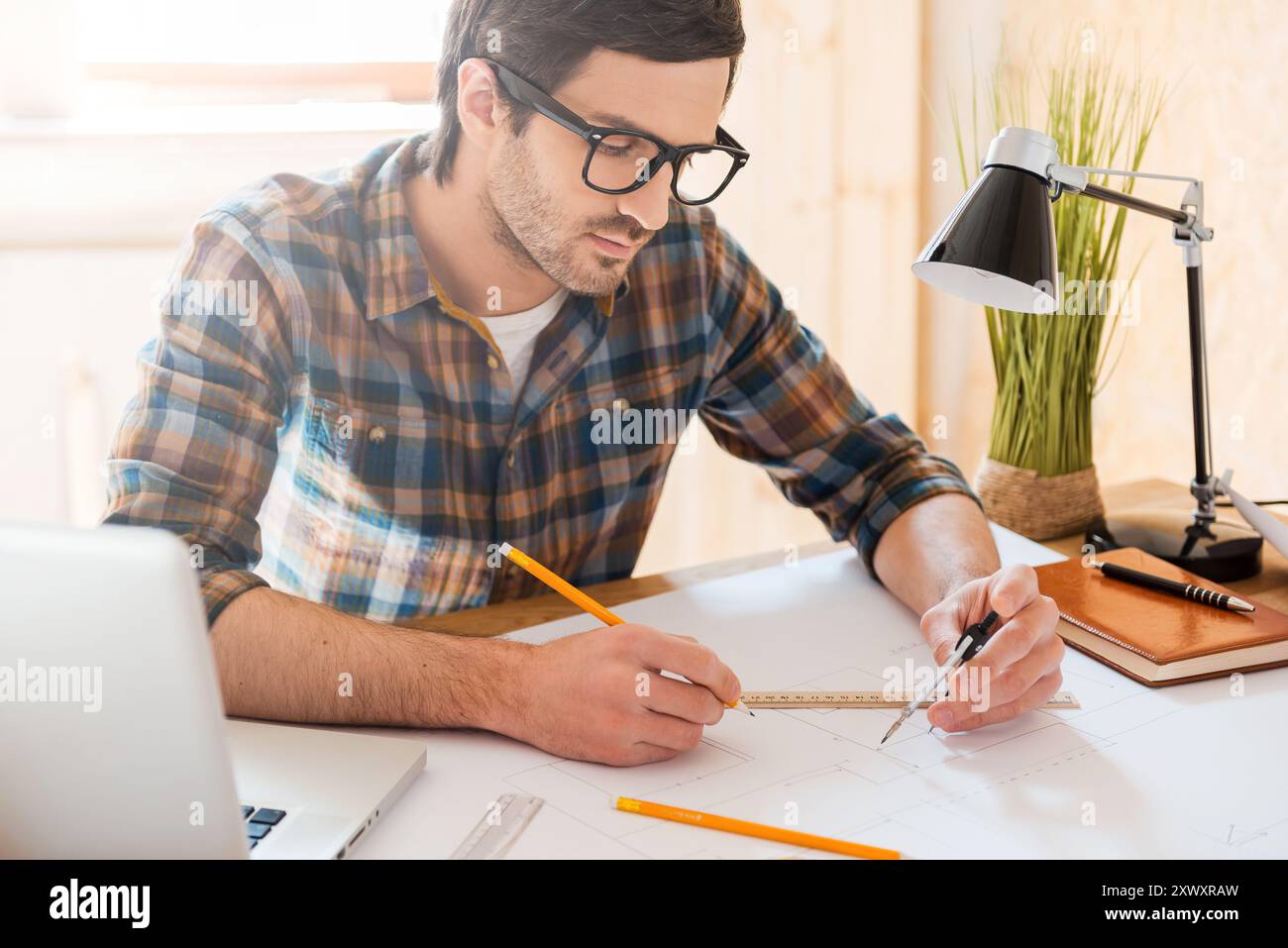 Bringing his ideas to life. Concentrated young man drawing while ...