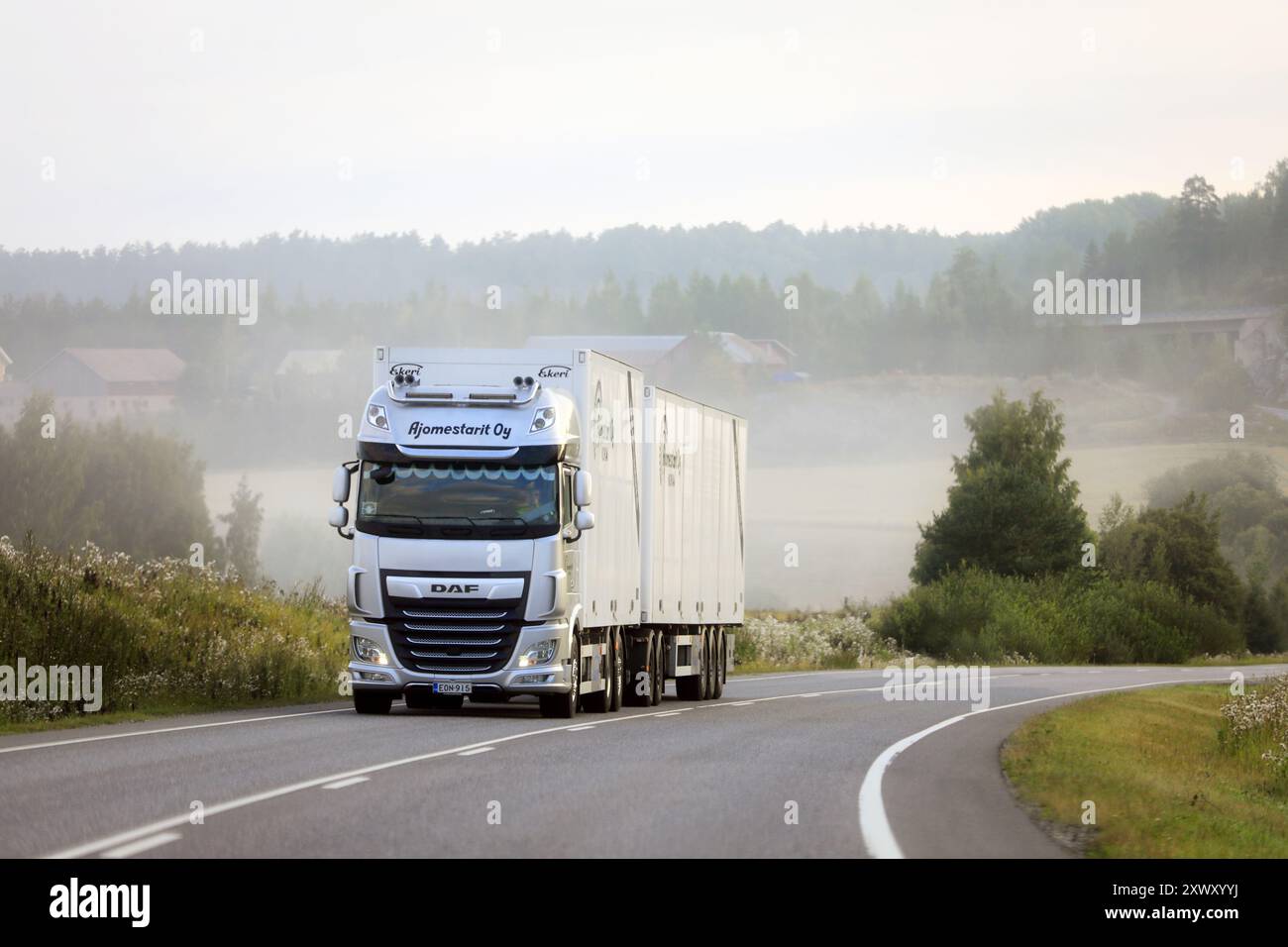 Silver DAF XF heavy truck pulls freight trailer along rural highway on ...