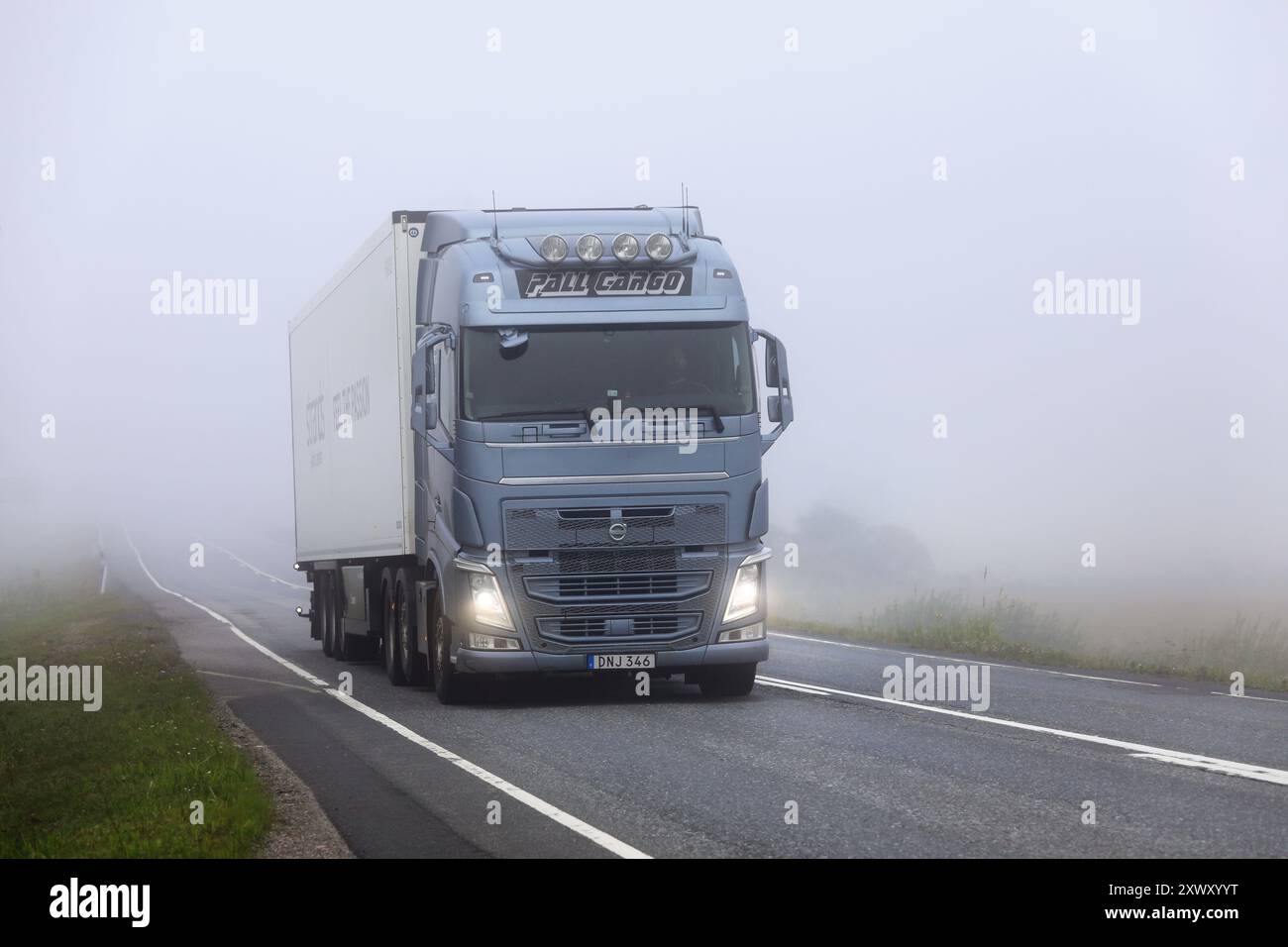 Light blue Volvo FH truck semi trailer emerging from fog as it is ...
