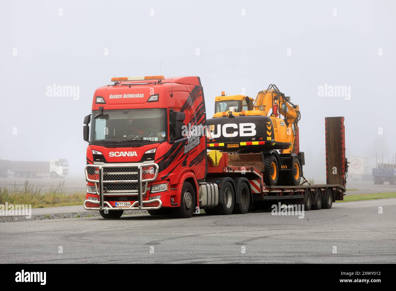 Red Scania truck drop deck trailer parked on a yard on a foggy morning ...