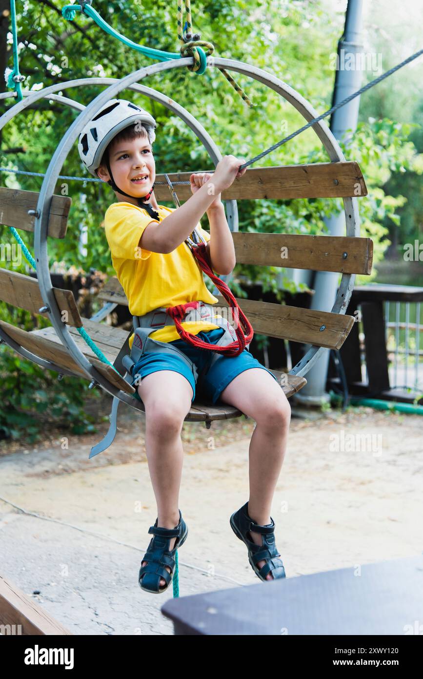 A boy is rock climbing in a rope park, walking along a cable car and ...