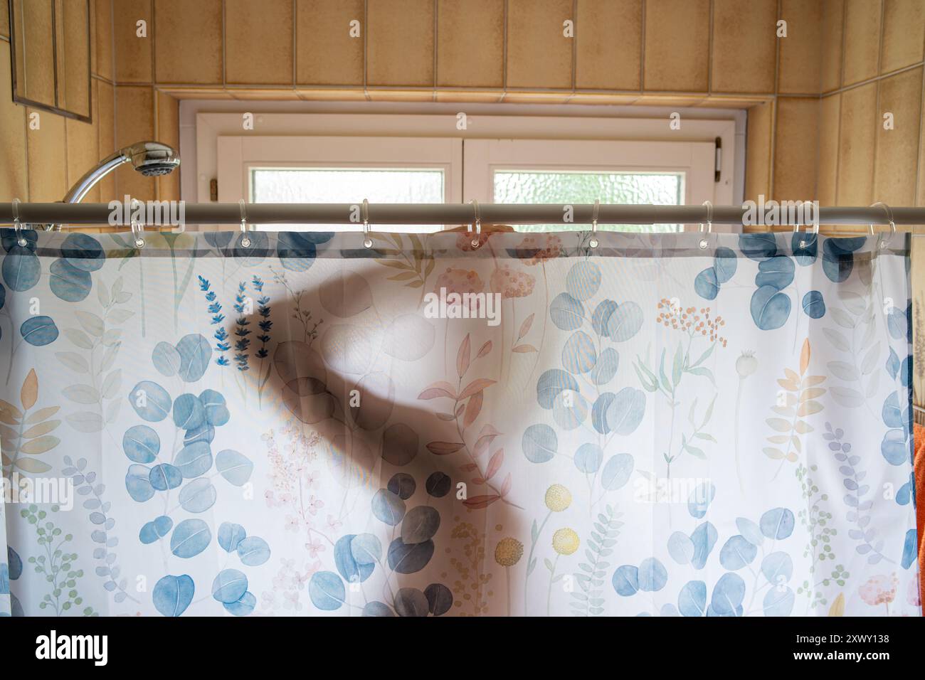 Unrecognizable man's silhouette taking a shower, seen through a shower ...