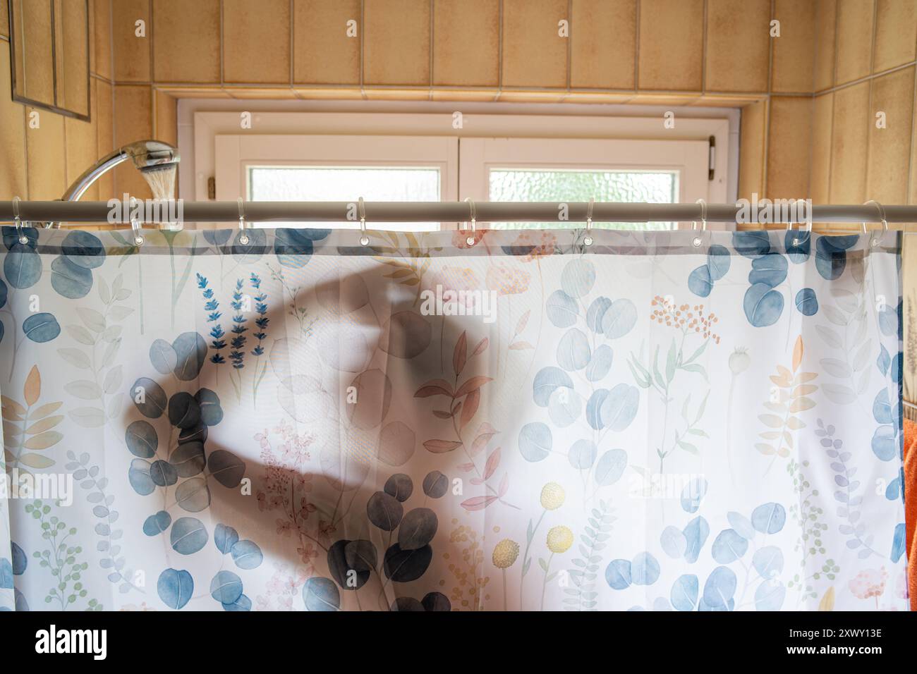 Unrecognizable man's silhouette taking a shower, seen through a shower ...