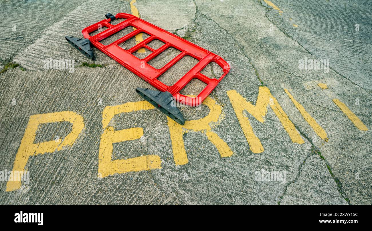 Painted 'permit' sign surface of on car park with fallen red traffic ...