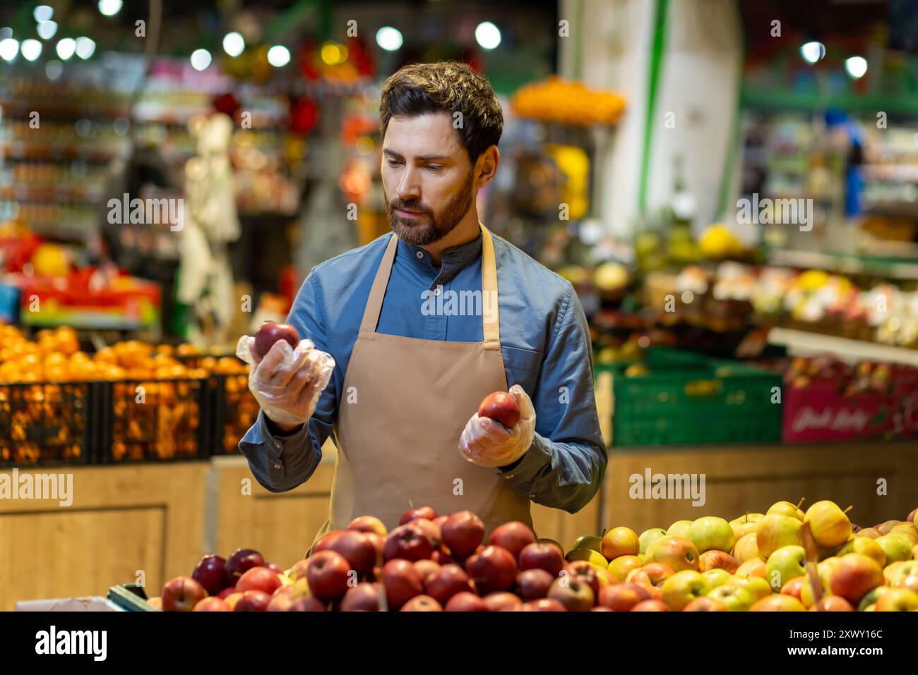 Grocery store worker organizing apples in produce section, emphasizing ...