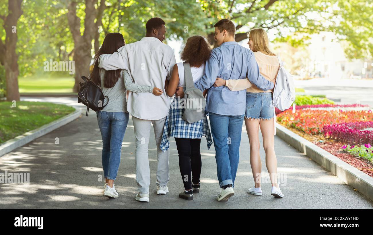 Back view of students friends hugging and walking by park Stock Photo ...
