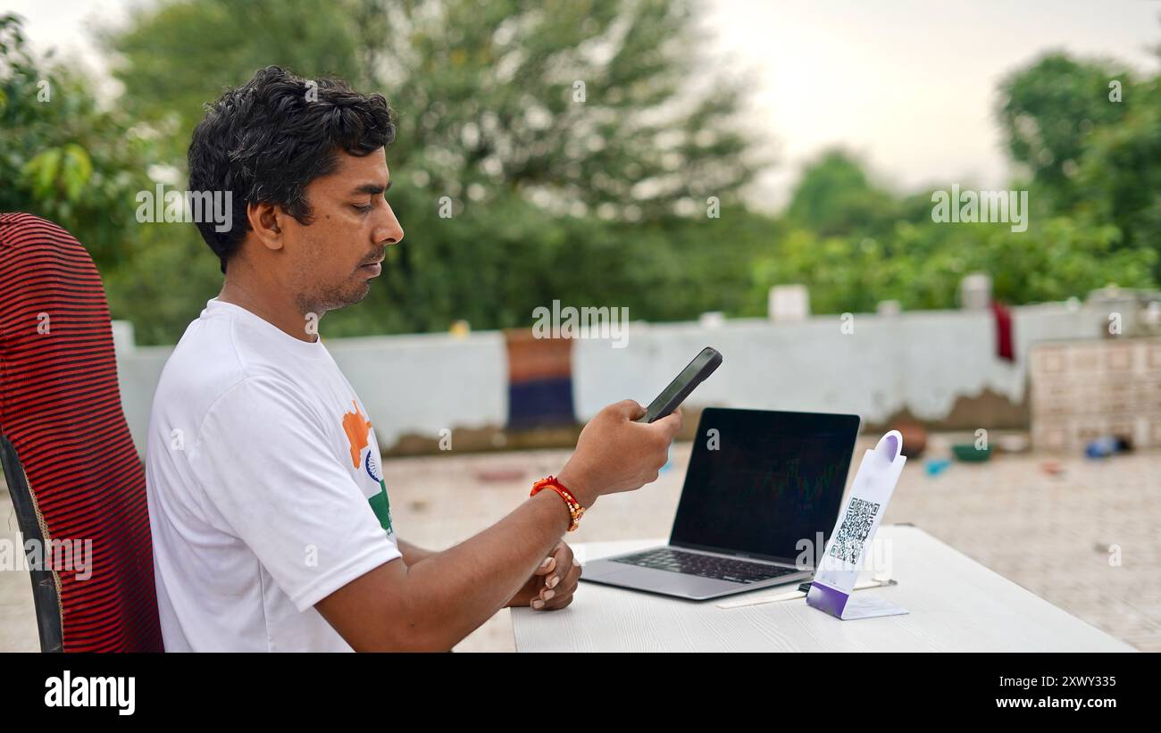 Young Indian man paying bills using mobile and laptop. QR code scan and ...