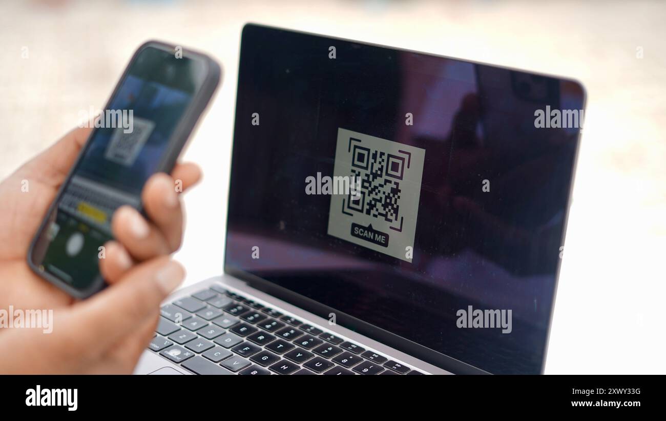 Young Indian man paying bills using mobile and laptop. QR code scan and ...