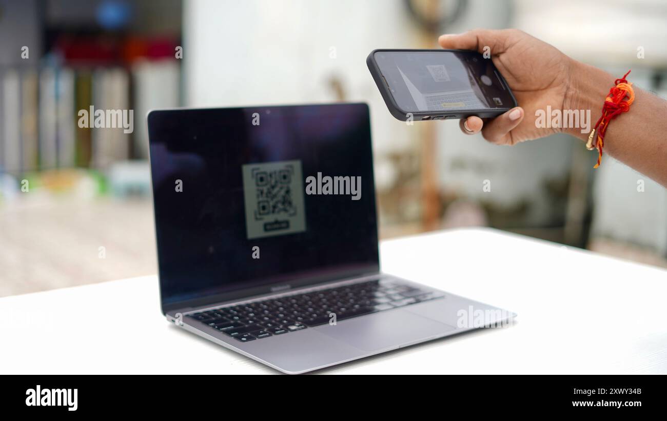 Young Indian man paying bills using mobile and laptop. QR code scan and ...