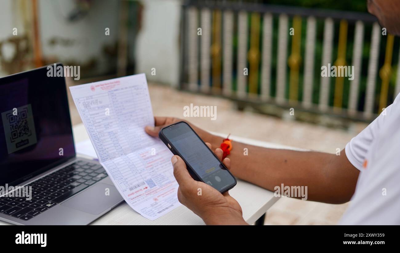 Young Indian man paying bills using mobile and laptop. QR code scan and ...