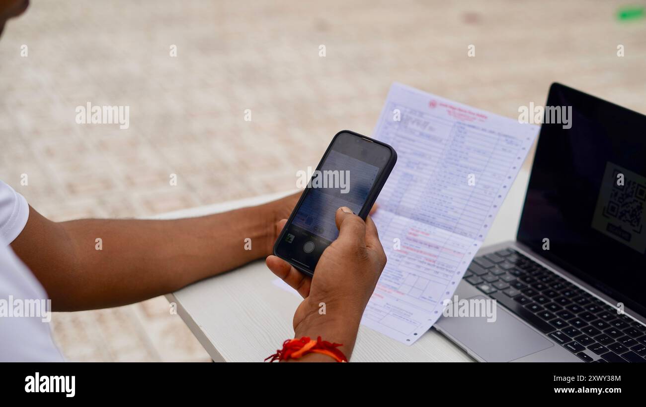 Young Indian man paying bills using mobile and laptop. QR code scan and ...