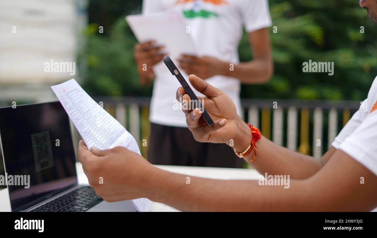 Young Indian man paying bills using mobile and laptop. QR code scan and ...