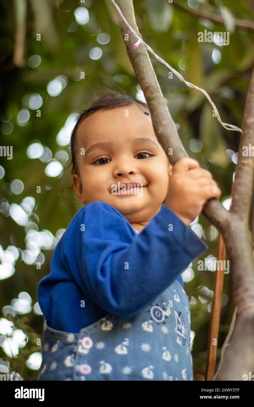 innocent toddler holding tree branch with cute facial expression at day from flat angle Stock ...