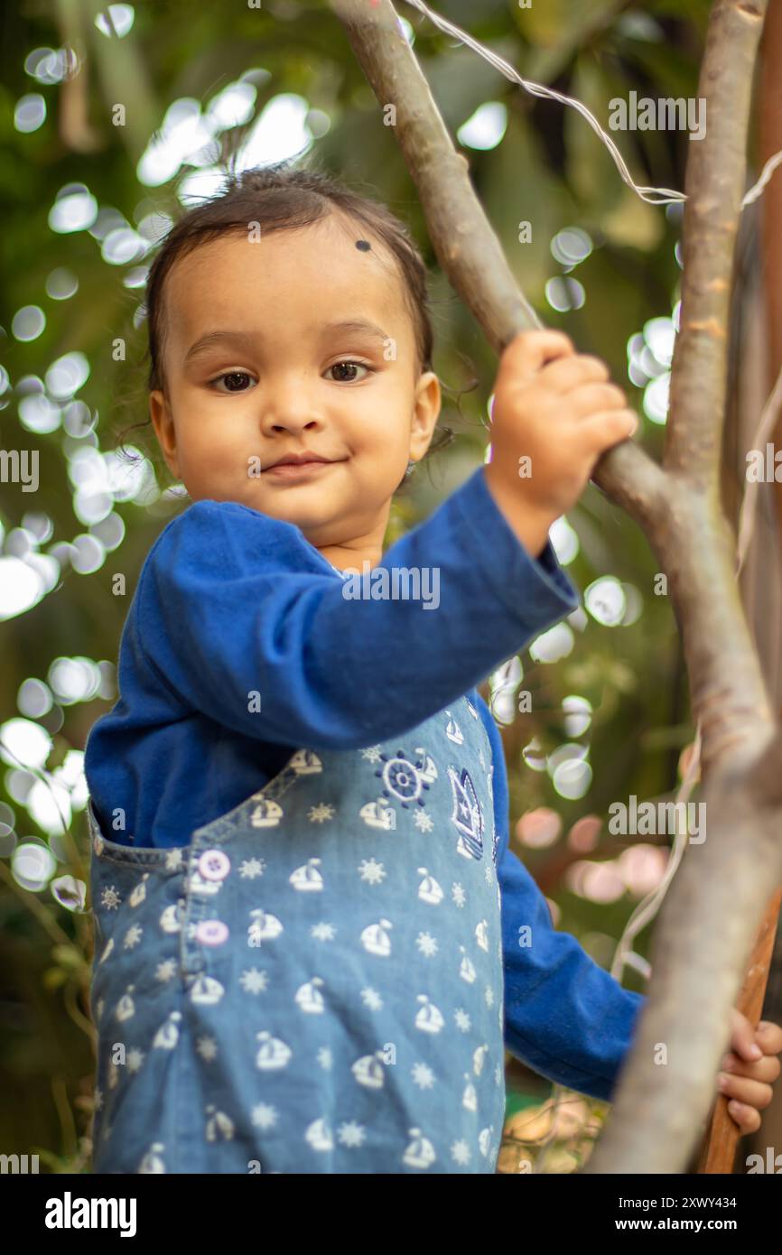 innocent toddler holding tree branch with cute facial expression at day ...