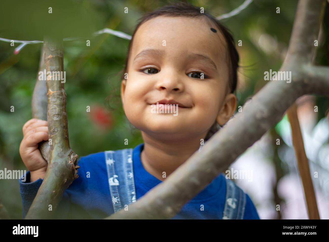 innocent toddler holding tree branch with cute facial expression at day ...