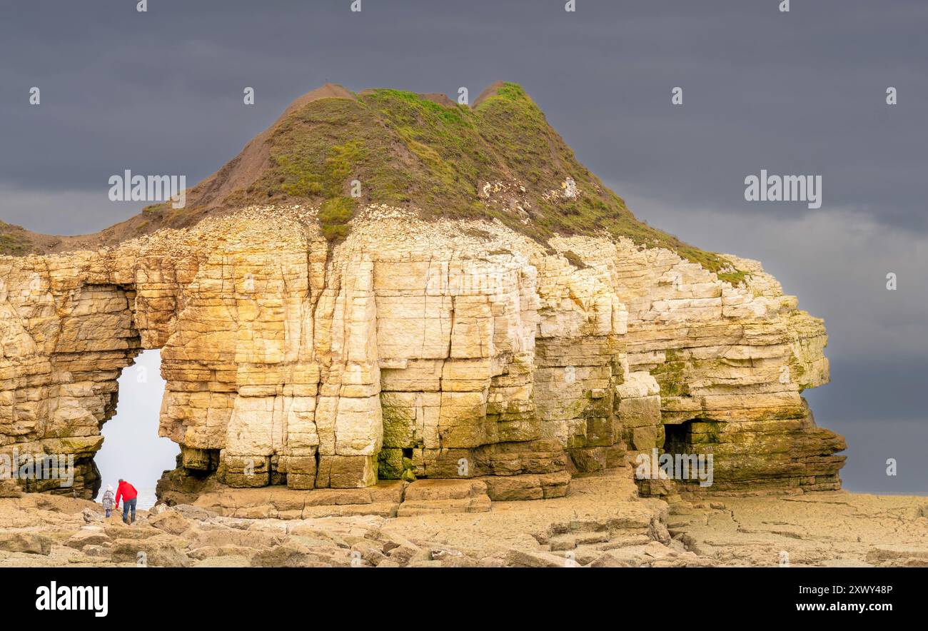 Sea arch on a chalk beach with figures in the distance Stock Photo - Alamy