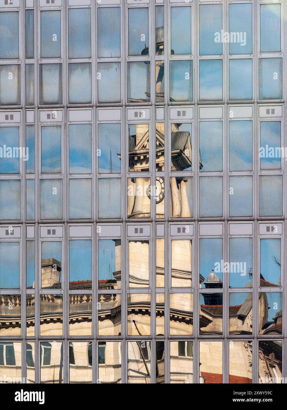 Abstract image of clock tower reflected in a modern glass building ...